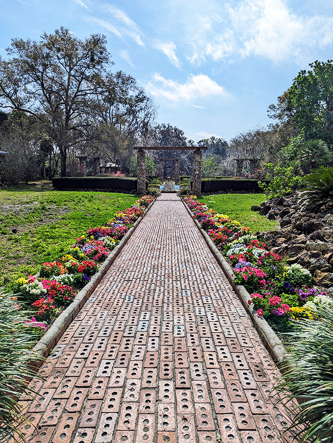 A brick pathway lined with vibrant flowers creates a royal runway through the gardens, inviting visitors to strut like nature's VIPs.