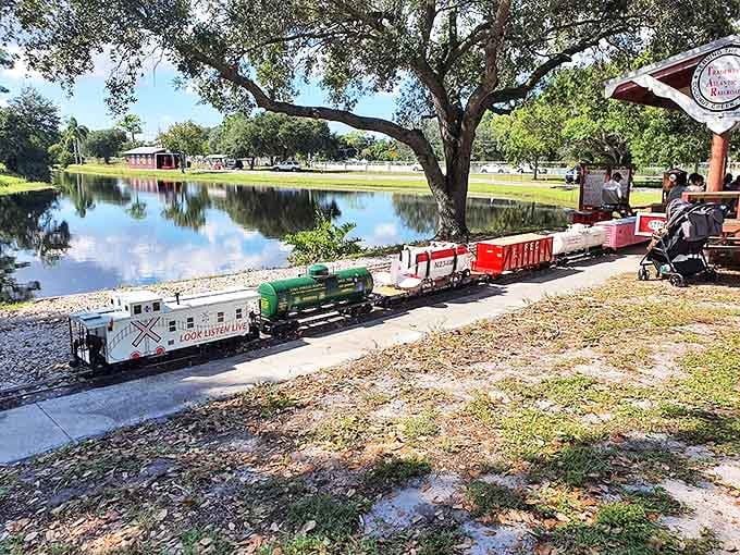 Colorful freight cars roll alongside the reflective pond, creating a perfect mirror image of childhood wonder.