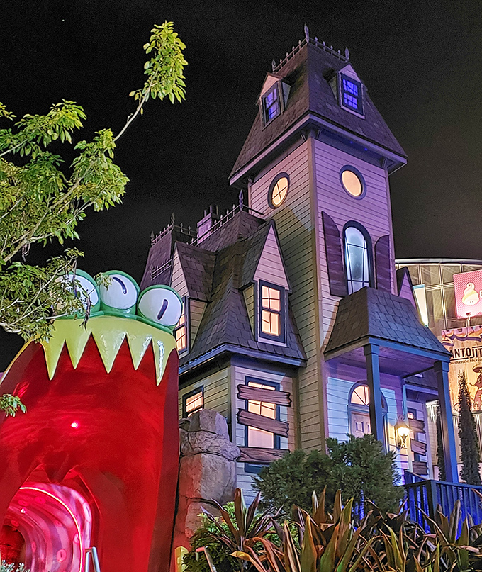 The haunted mansion looms ominously against the night sky, its windows glowing with supernatural light that beckons brave golfers.
