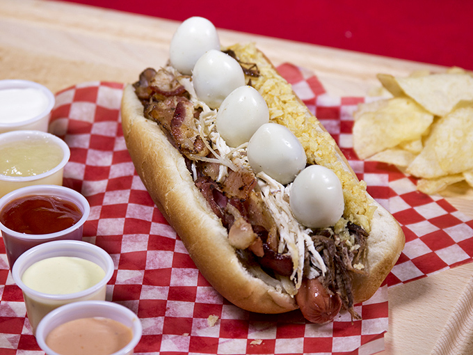 Not your childhood hot dog! This masterpiece comes loaded with quail eggs, bacon, and enough toppings to require an engineering degree to eat.