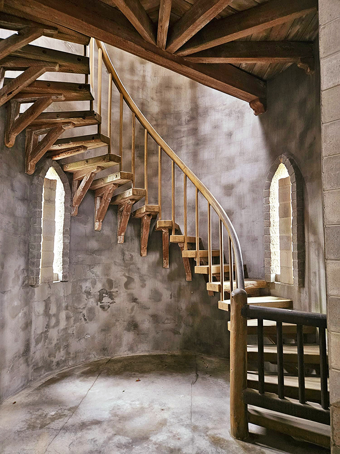 This winding wooden staircase seems to float against curved stone walls, inviting visitors upward on a journey through time.