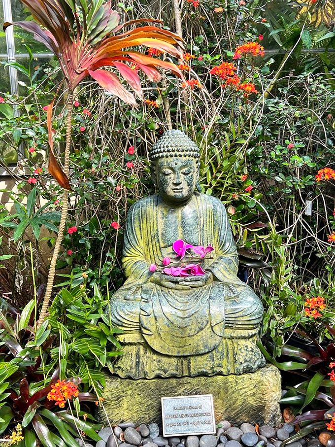 Buddha sits serenely among tropical blooms, looking like he knows something wonderful that he's not quite ready to share.