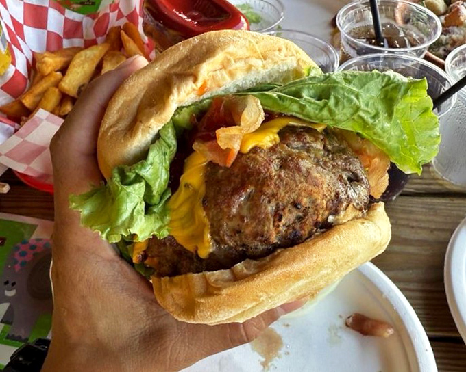Holding this burger requires both hands, serious commitment, and the willingness to accept that your shirt may become collateral damage in this delicious battle.