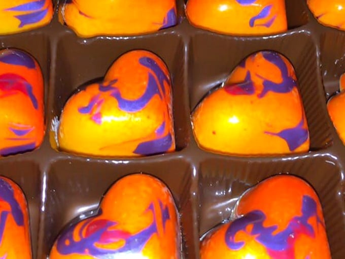 Artisanal chocolates with vibrant orange and purple swirls tempt sweet-toothed night owls, proving that Gothic indulgence extends beyond just the liquid variety.