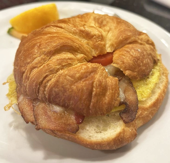 Breakfast sandwich perfection: golden croissants cradle eggs and bacon in a morning masterpiece worth setting the alarm for.