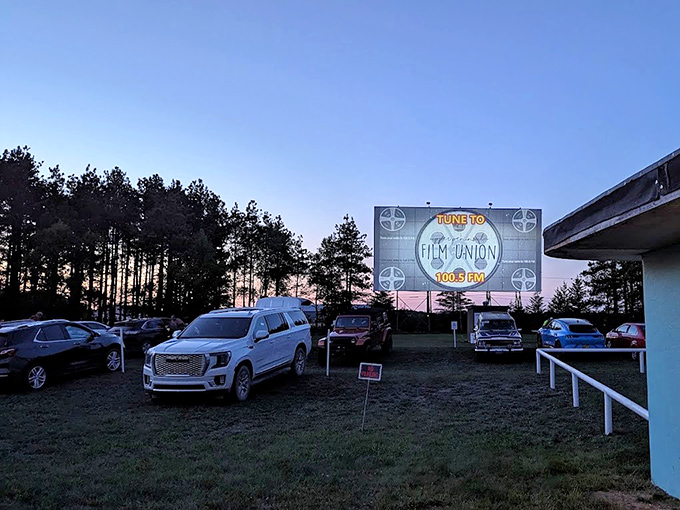 Dusk settles over Highway 2 Drive-In as vehicles find their perfect viewing spots, headlights dimming in anticipation.