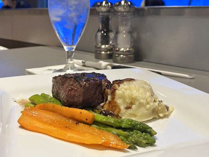A perfectly cooked filet mignon with seasonal vegetables proves that even with sharks as the backdrop, the food refuses to be upstaged.