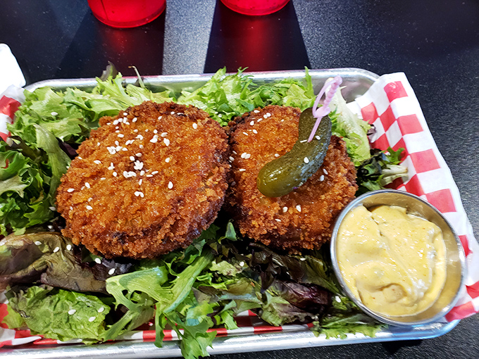 Golden-fried crab cakes rest on a bed of fresh greens, offering a sophisticated twist on a classic appetizer.