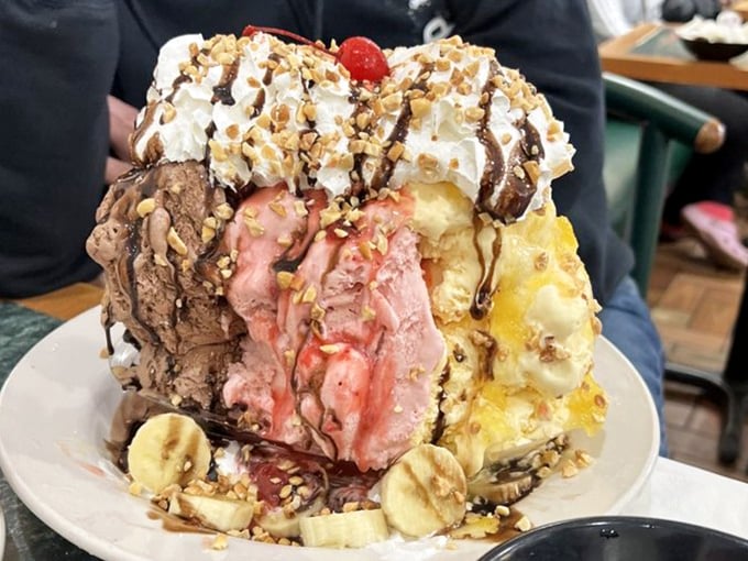This isn't just dessert, it's an architectural marvel &ndash; scoops the size of softballs balanced on banana foundations with chocolate drizzle reinforcing the structure.