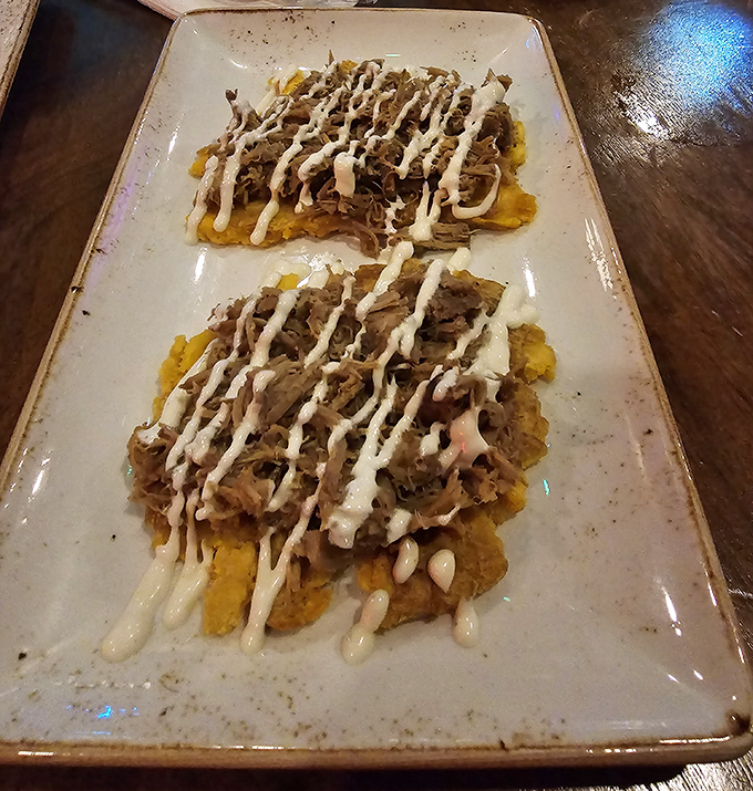 Twice-fried plantains create the perfect foundation for succulent mojo-marinated meat, finished with a zigzag of sauce that's both artful and delicious.