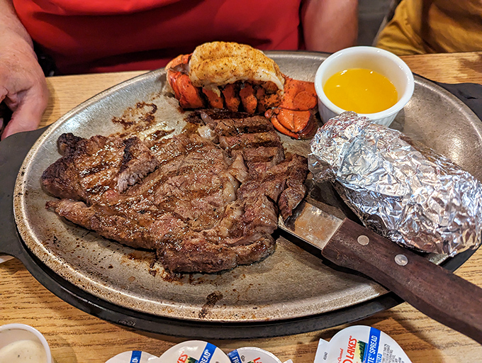 Surf meets turf in glorious harmony, with a perfectly cooked steak sharing the plate with a butter-drenched lobster tail and foil-wrapped potato.