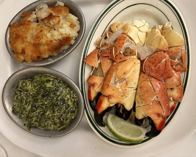Beautifully presented stone crab claws with fresh lime, paired perfectly with creamy spinach and crispy potatoes for an impressively appetizing meal.