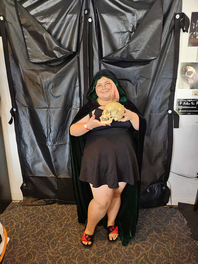 A visitor poses with a skull, embodying the museum's blend of educational purpose and the natural human fascination with mortality.