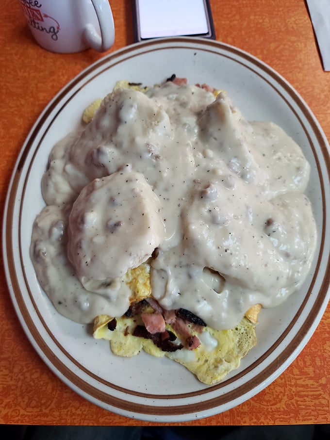 Breakfast architecture at its finest: eggs and ham peeking out beneath a blanket of country gravy that's thicker than a UP winter coat.