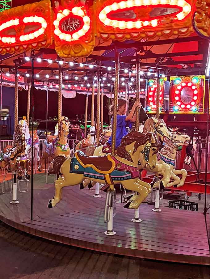 Meticulously painted horses frozen mid-gallop, their golden poles gleaming under carnival lights as they await their next riders.