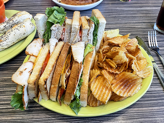 A sandwich that requires both hands and possibly a bib – layers of tender chicken, fresh greens, and house-made chips that crunch like autumn leaves.