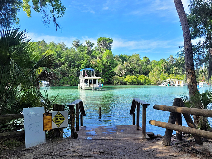 A simple wooden dock extends invitation to paradise, where boats bob gently on waters that shimmer like melted sapphires.