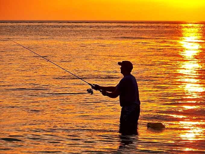 Golden hour angler: A fisherman casts his line into the sunset-painted waters, embodying Siesta Key's perfect blend of leisure and natural beauty.