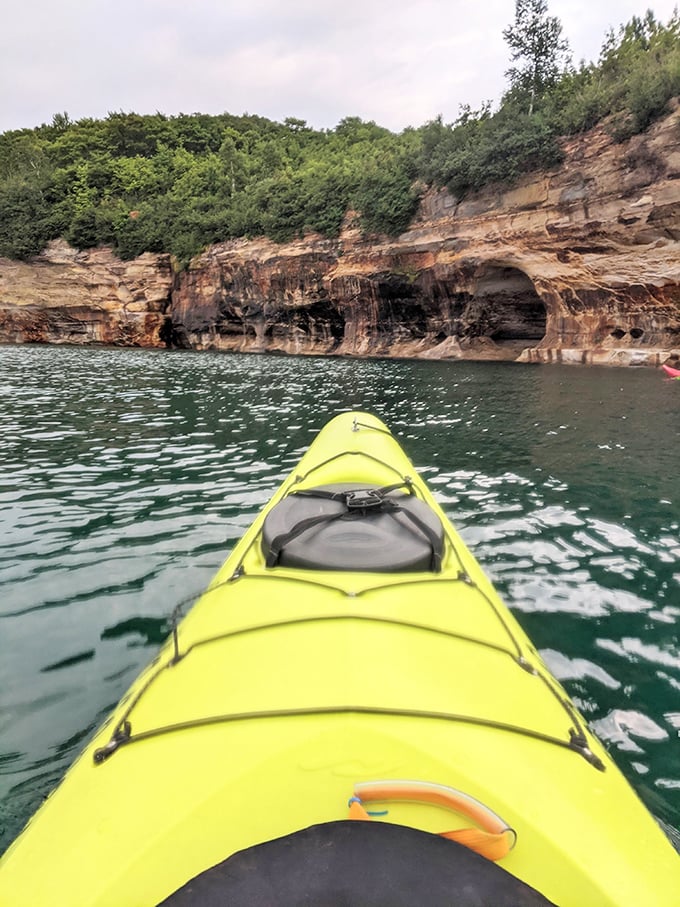 Bright yellow kayaks provide perfect contrast against the emerald waters, offering adventurers an up-close encounter with geological wonders.