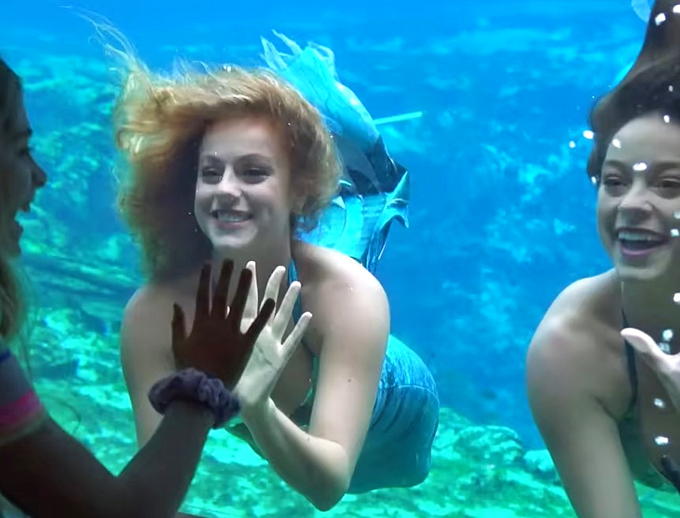 The underwater meet-and-greet moment captures the joy of connection between performers and audience through the theater's viewing windows.