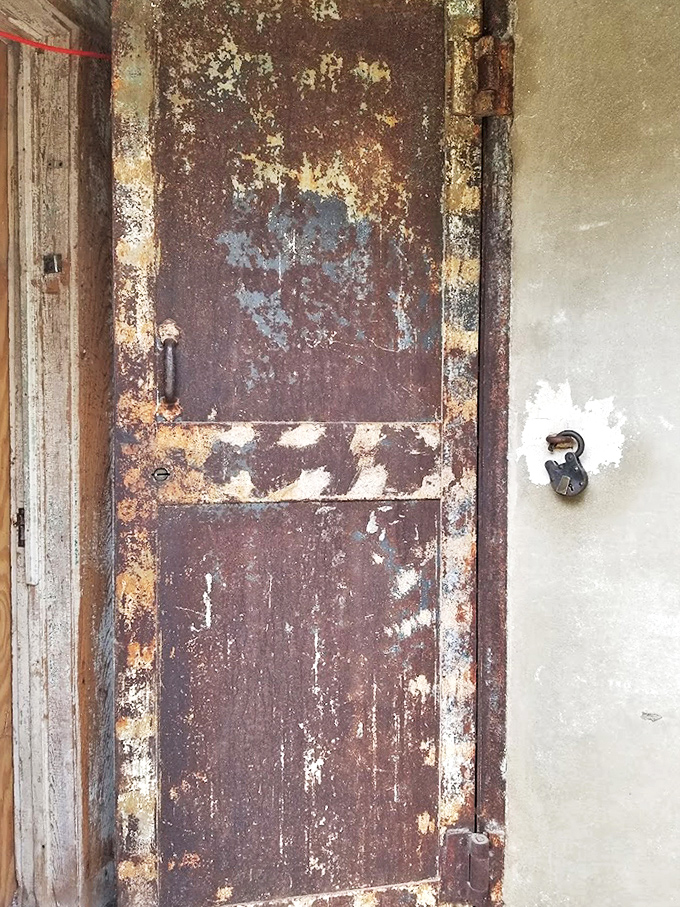 Rust creeps across this cell door like slow-motion flames, consuming what was once impenetrable. The lock remains, but who holds the key now?