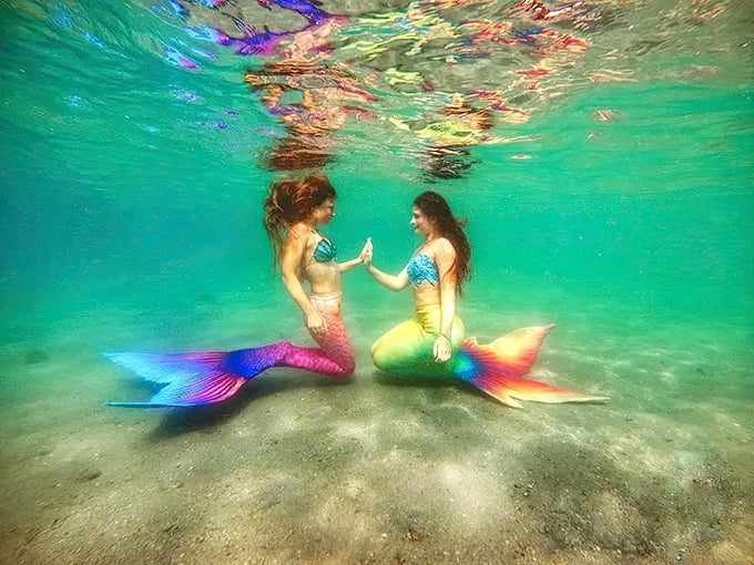 Two mermaids share an underwater high-five, proving that even mythical sea creatures appreciate a good celebration.