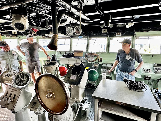 Visitors explore the bridge where captains once commanded this floating city of steel through peaceful waters and combat zones alike.