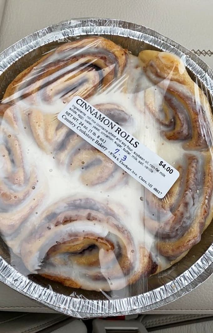 A cinnamon roll so generously frosted it looks like it's wearing a delicious winter coat, ready to warm your soul one bite at a time.