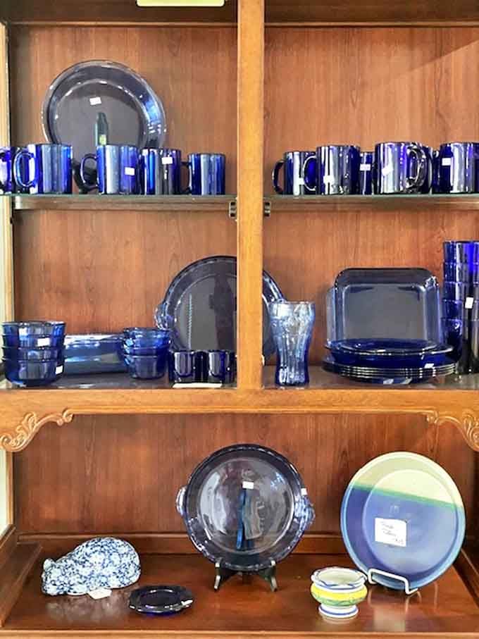 Cobalt blue glassware catches the light like sapphires on wooden shelves, each piece more vibrant than anything you'd find in today's department stores.