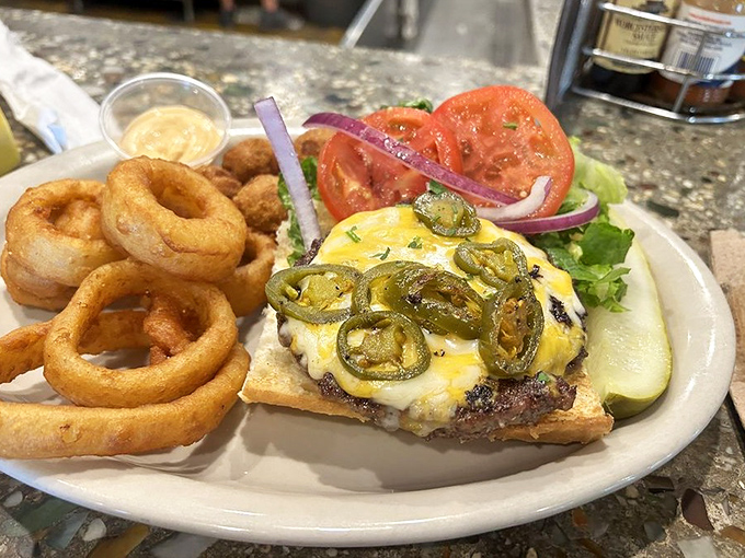 This isn't just lunch &ndash; it's architecture: perfectly stacked beef, melted cheese, jalape&ntilde;os, and crispy onion rings creating edible harmony.