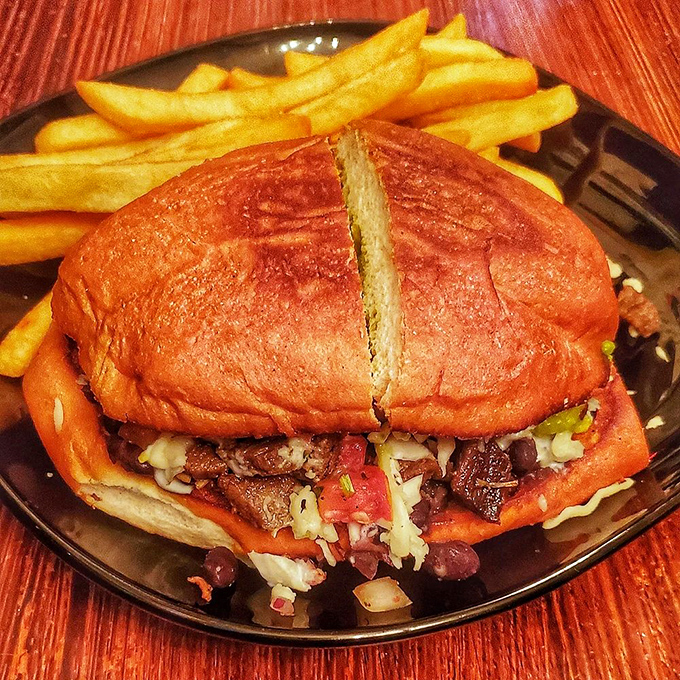 A sandwich that requires both hands and a strategy, stuffed with savory fillings between toasted buns that somehow contain the delicious chaos within.