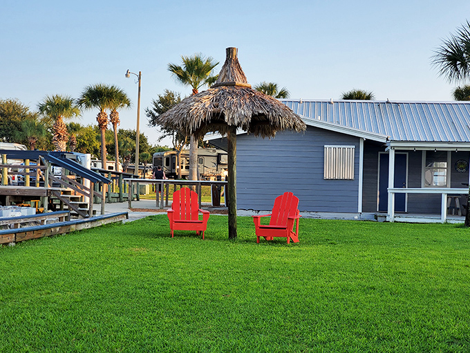 Red Adirondack chairs await beneath a thatched umbrella &ndash; nature's perfect office for professional relaxation specialists (also known as vacationers).