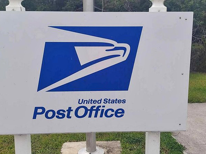 The iconic USPS eagle logo seems almost comically oversized compared to the diminutive building it represents.