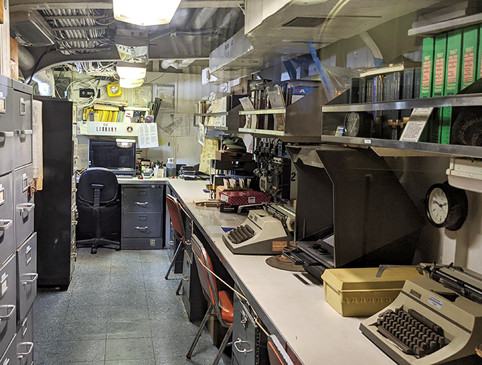 Vintage typewriters and naval equipment fill the ship's office space, where the paperwork of war was once meticulously managed.