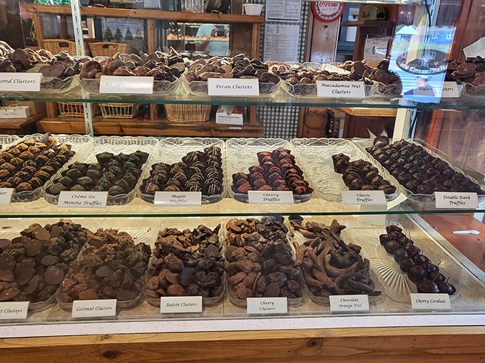 The chocolate case offers a mesmerizing selection of clusters, barks, and specialty treats arranged like edible jewels.