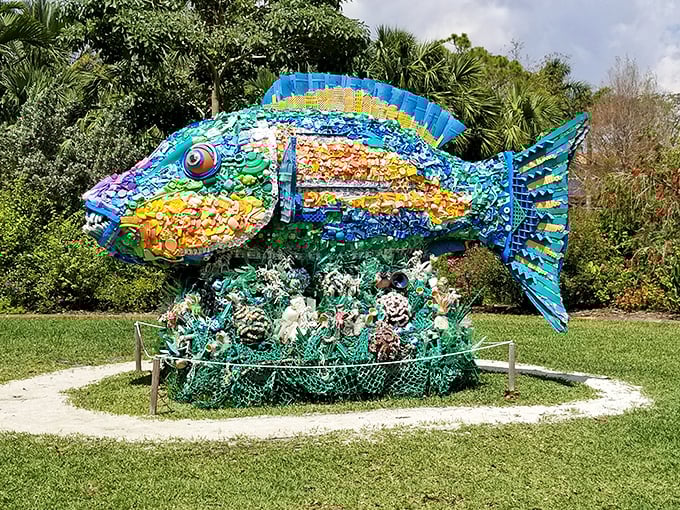 A kaleidoscope of recycled materials transforms into a vibrant fish sculpture, swimming through a sea of green at Mounts Botanical Garden.
