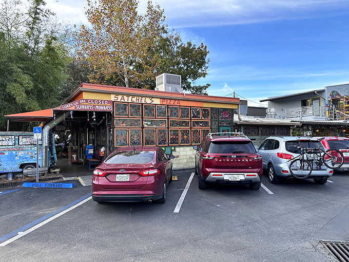 The eclectic charm of Satchel's Pizza includes parking area and a sign announcing their famous "closed Sundays and Mondays" policy.