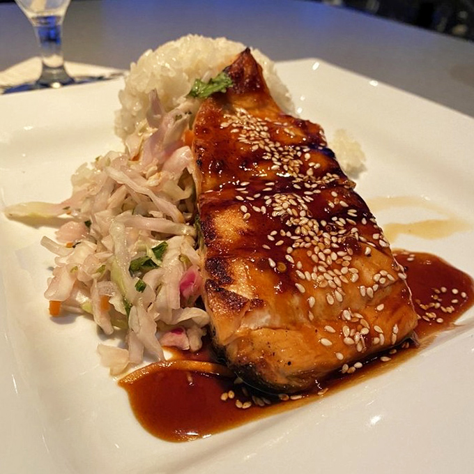 The miso-roasted Atlantic salmon arrives with a side of irony, as its distant cousins swim freely on the other side of the glass.