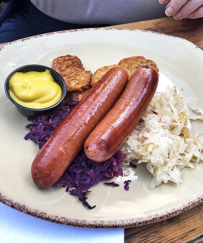 Authentic German sausages snap with that perfect resistance, nestled on tangy sauerkraut and served with potato pancakes that would make any Bavarian grandmother proud.