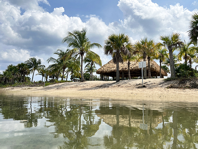 Thatched perfection! This charming beach hut mirrors in calm waters, offering shade and style for sun-soaked island adventurers.