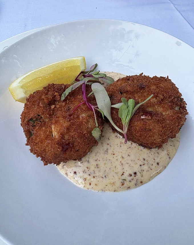 Golden-brown treasures of the sea sit atop a velvety sauce, garnished with microgreens and a lemon wedge for that perfect citrus finish.