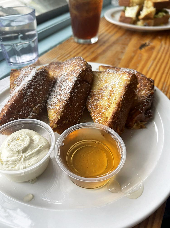 Golden-brown challah triangles with a side of maple syrup and cream &ndash; breakfast elevated to an art form.
