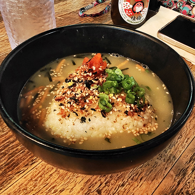 A chilled Hitachino Nest ale waits beside a comforting rice bowl topped with fresh garnishes.