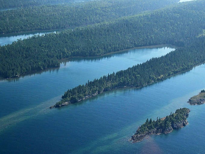 The aerial view reveals Lake Superior's islands like emerald jewels scattered across blue velvet, each one a little wilderness waiting to be explored.