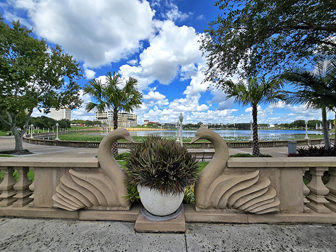 Swan sculptures stand sentinel along Lake Mirror's edge, their graceful stone forms echoing the garden's perfect balance of structure and natural beauty.