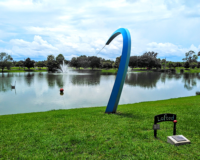 "Lofted" curves gracefully against the water, its blue form suggesting a fishing rod casting into the pond&mdash;art that plays with perception.