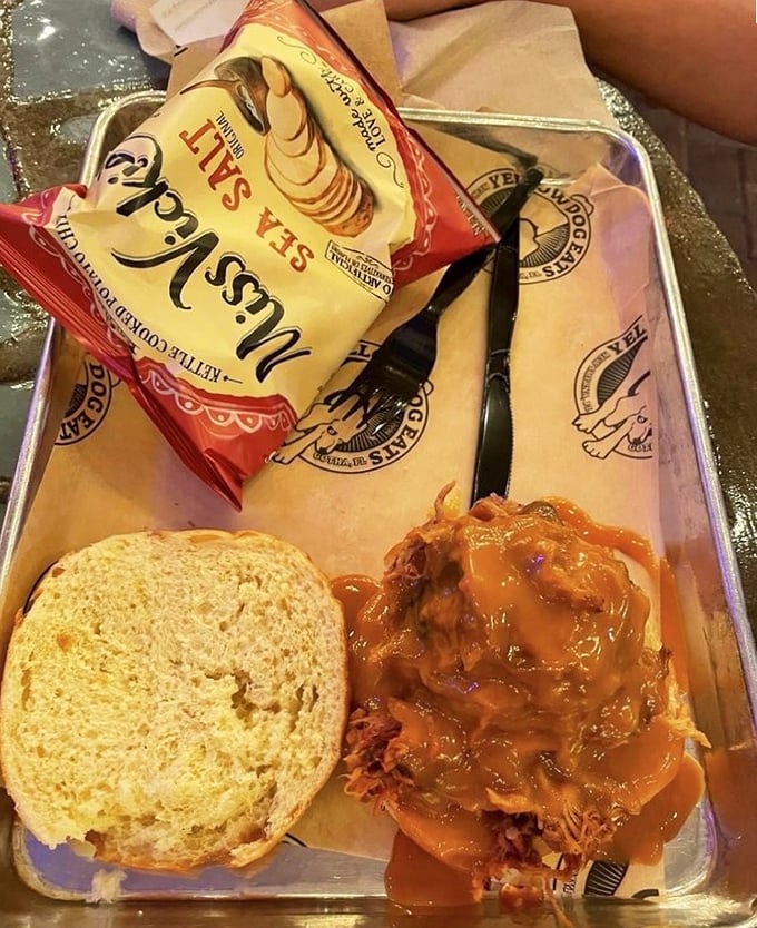 Simple perfection on a metal tray &ndash; pulled pork sandwich with kettle chips and homemade slaw, proving that sometimes the classics need no improvement, just excellent execution.