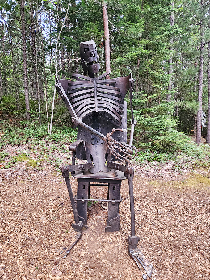 This contemplative metal skeleton sits among the pines like a philosophical reminder that even in art, we can find moments of existential reflection.