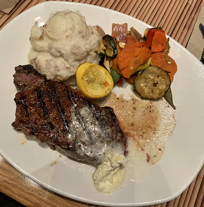 A perfectly grilled steak shares the plate with creamy mashed potatoes and colorful vegetables&mdash;comfort food in the heart of the jungle.