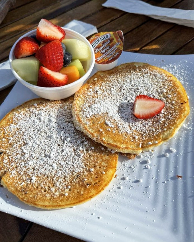 Pancakes dusted with powdered sugar and accompanied by fresh fruit &ndash; because calories don't count when you're this close to paradise.